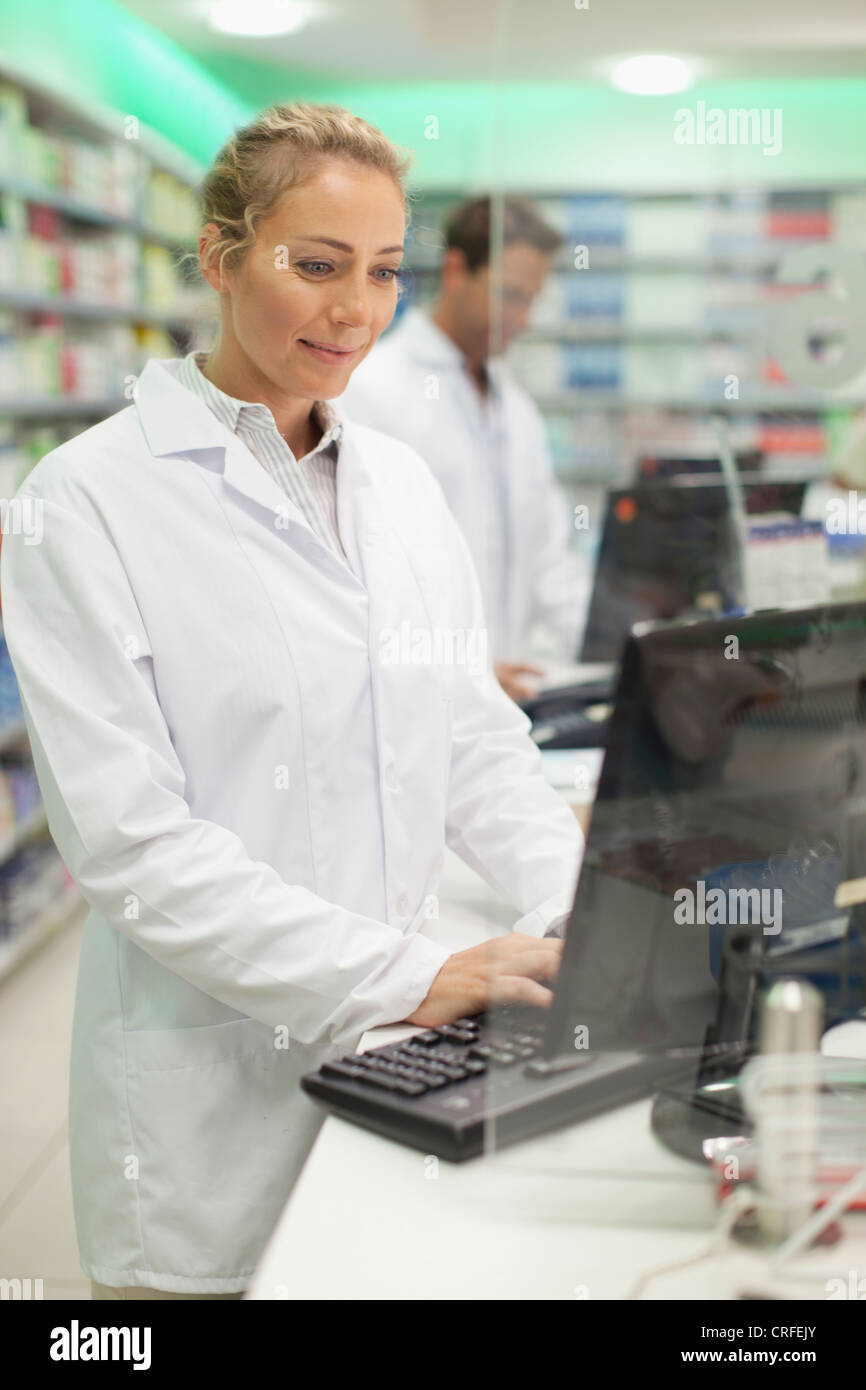 Pharmacist using computer at counter Stock Photo - Alamy