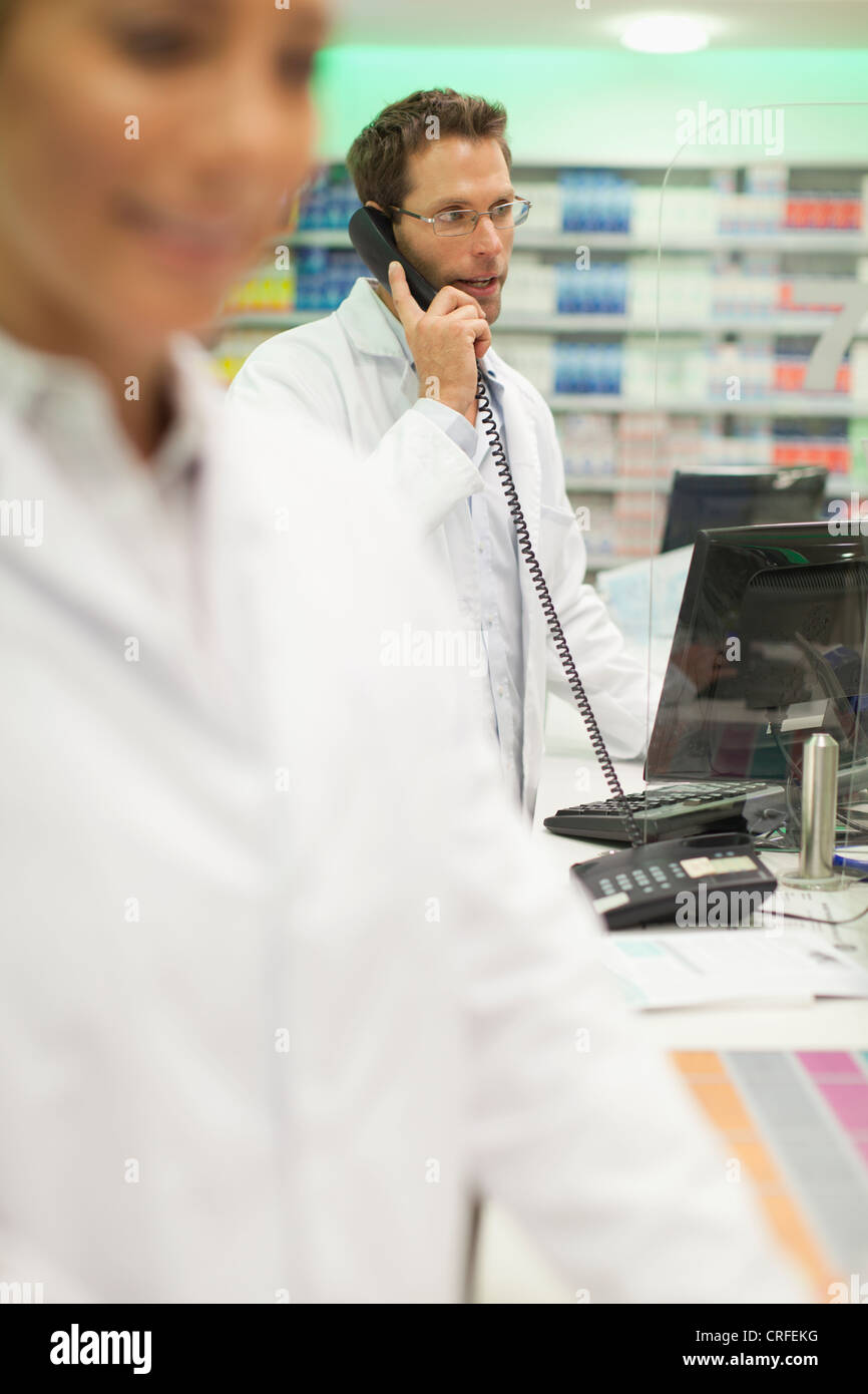 Pharmacist talking on phone at counter Stock Photo - Alamy
