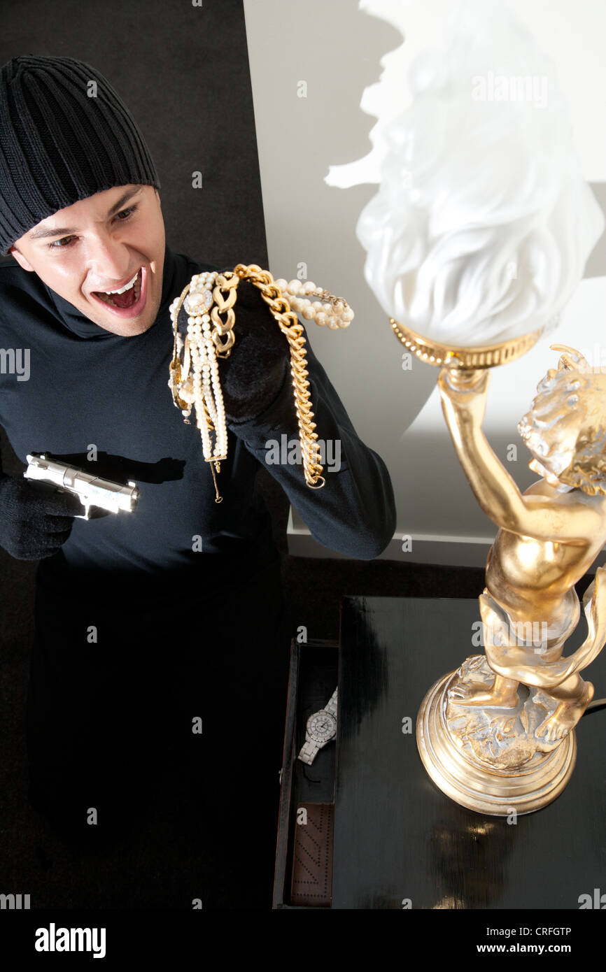 Excited young male burglar stealing expensive gold valuables Stock ...