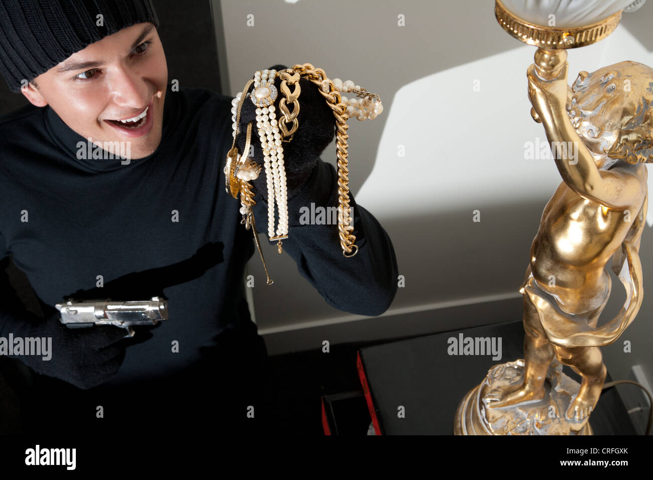 Cheerful burglar stealing expensive gold valuables Stock Photo - Alamy