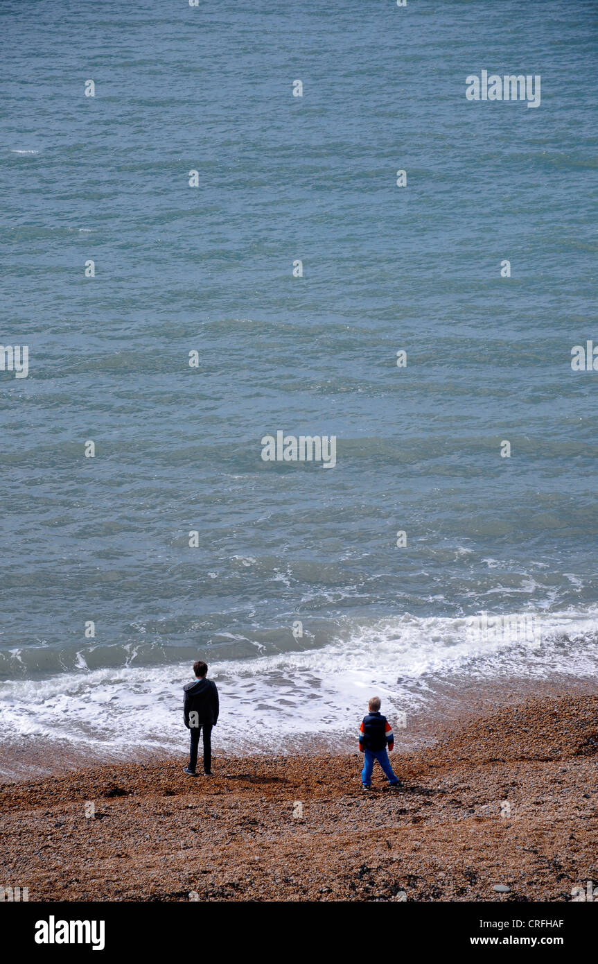 Two boys look out to sea on a beach at Eype in Dorset, England Stock ...