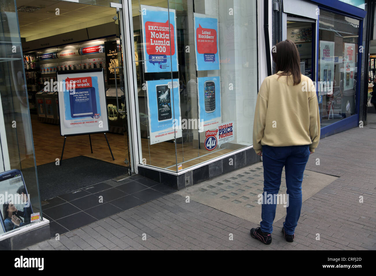 Woman Looking At Mobile Phones Advertised In Mobile Phone Shop Window ...