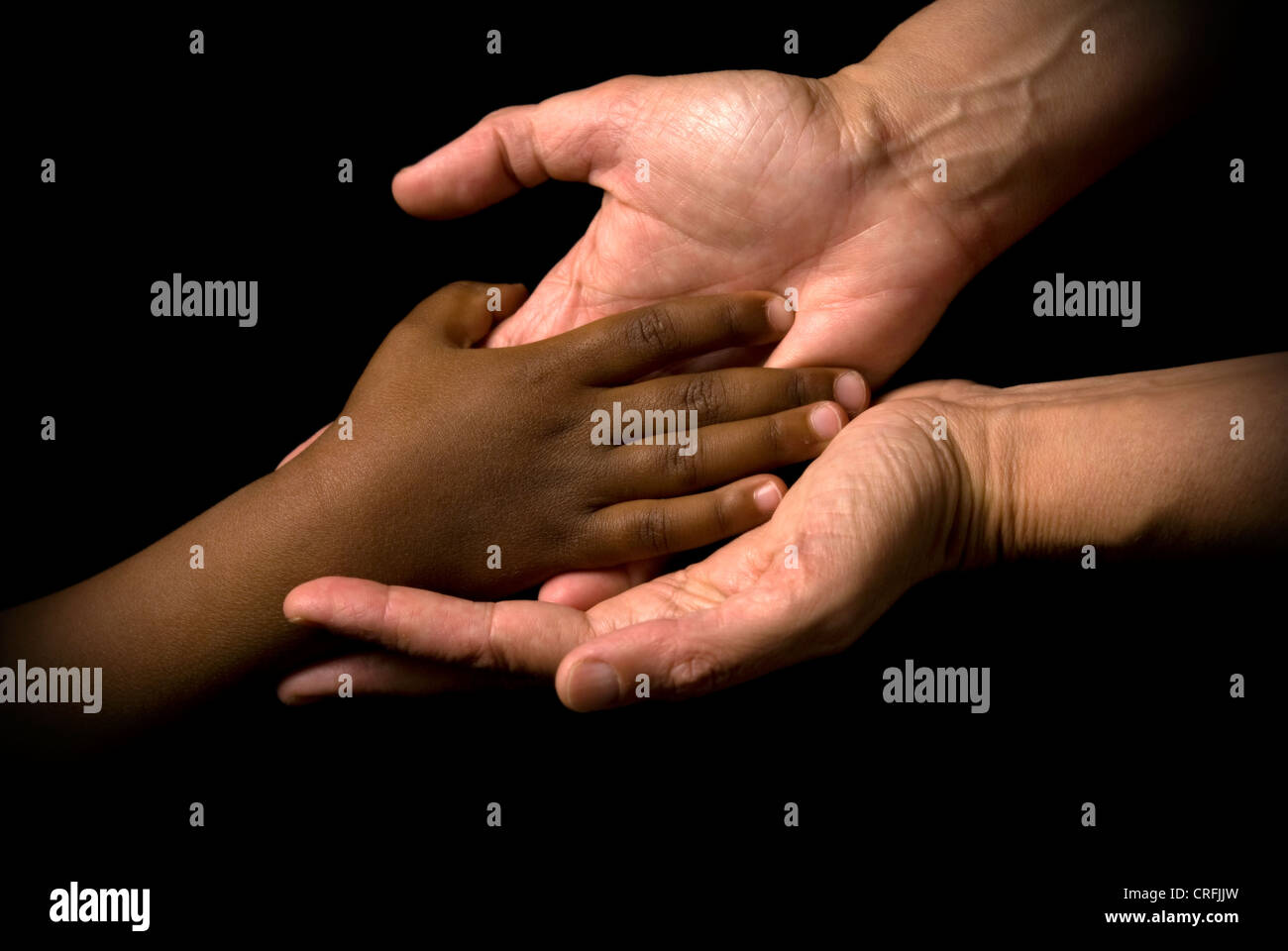 White woman's hands receive the black child's hand Stock Photo - Alamy