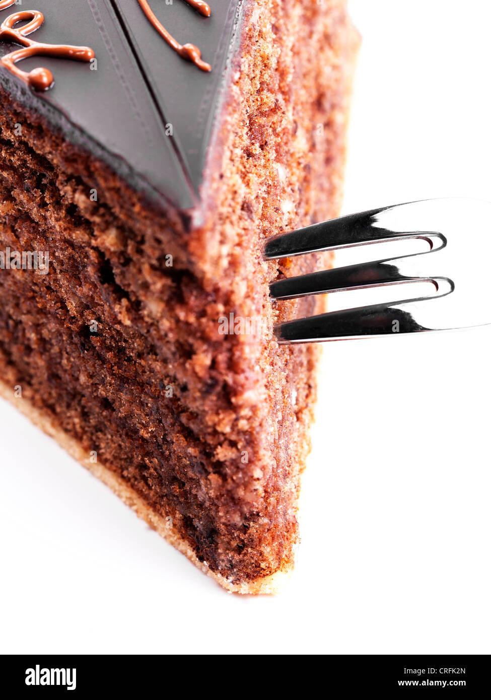 closeup from top of a fork in a chocolate cake on white background ...