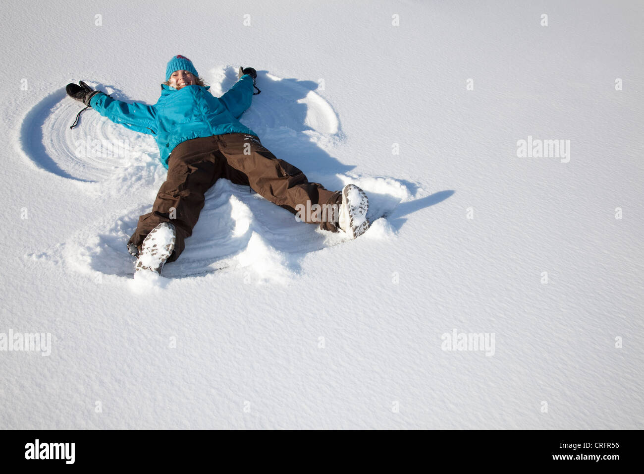 Woman making snow angel on field Stock Photo - Alamy
