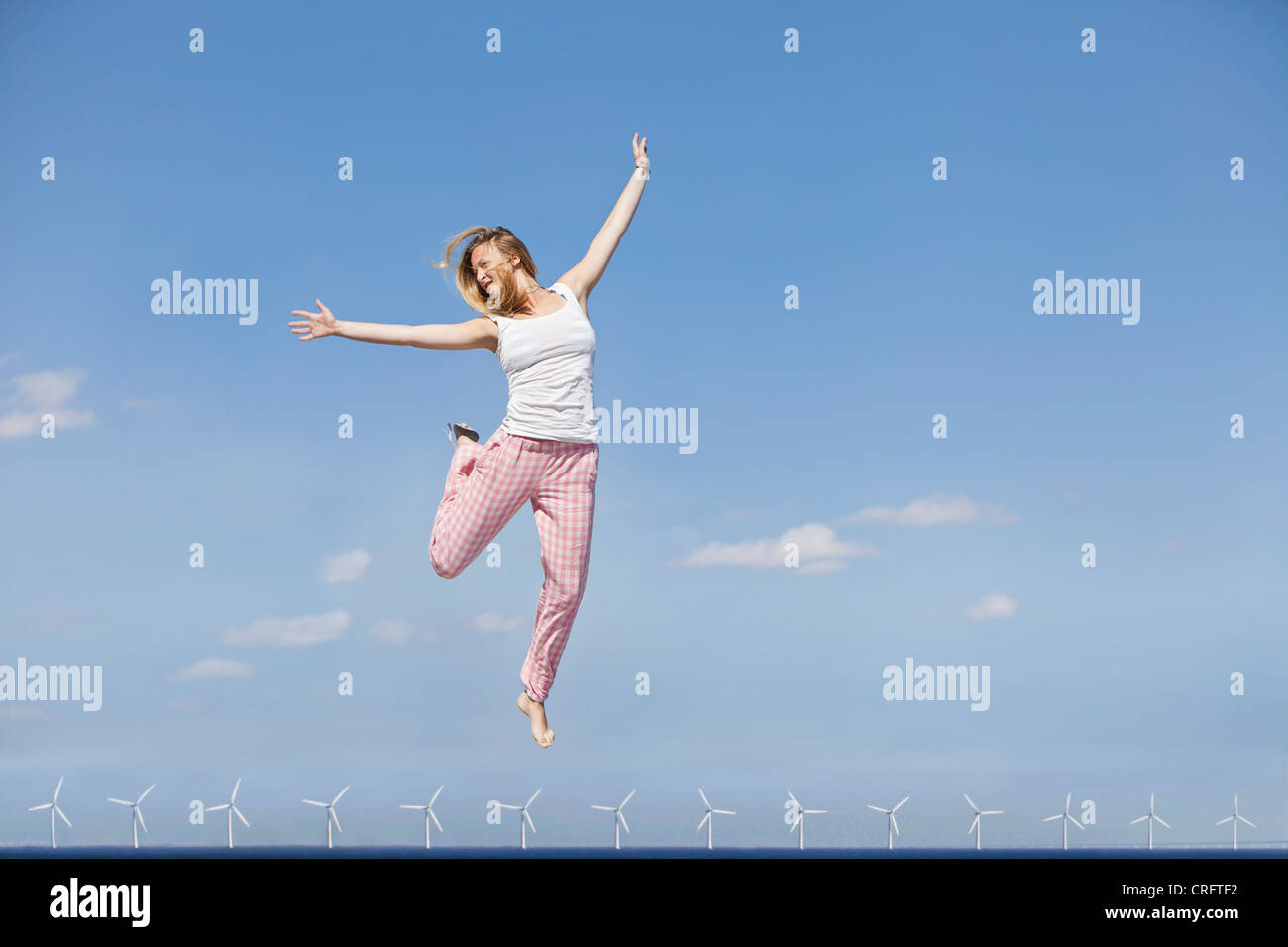 Woman jumping for joy over wind turbines Stock Photo - Alamy