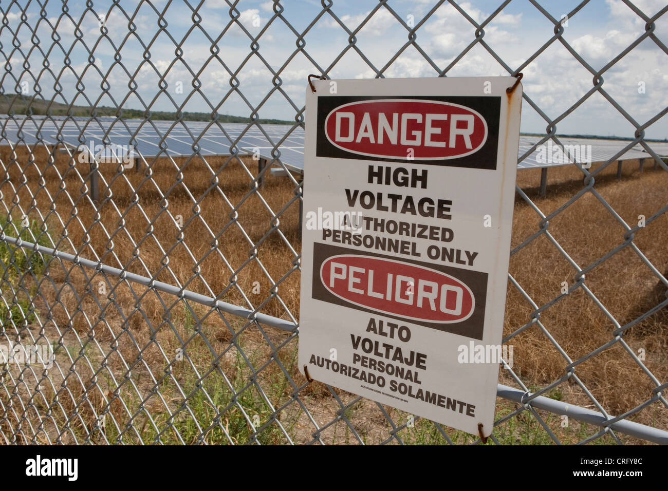 High voltage danger sign on chain link fence at solar power farm in ...