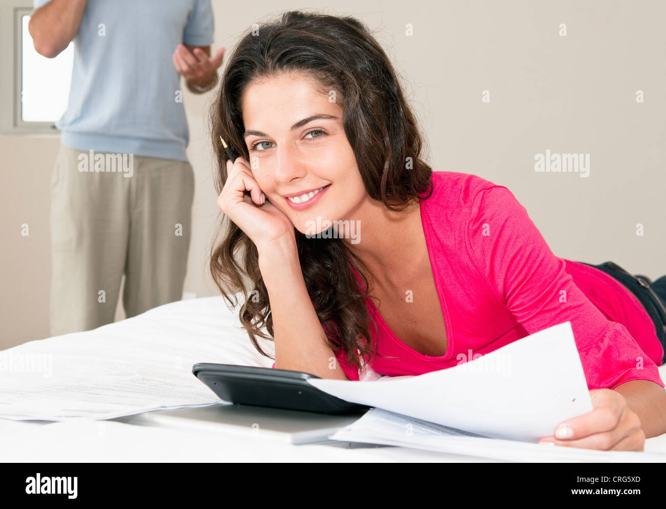 Woman using calculator on bed Stock Photo - Alamy