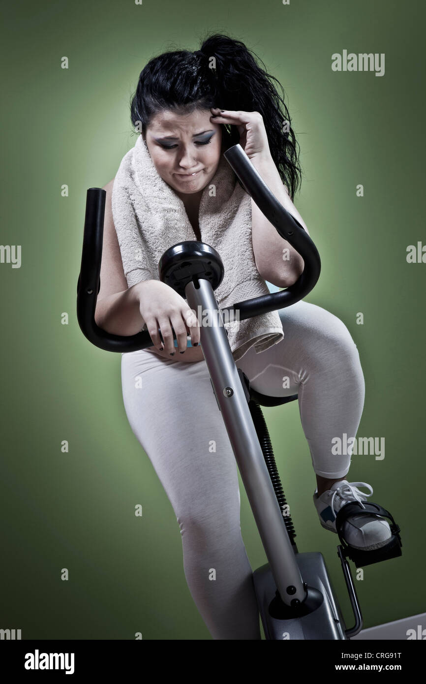Woman using exercise bike at home Stock Photo - Alamy