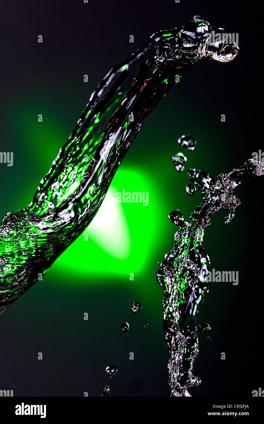 Water is thrown into the air taking on forms against the green ...