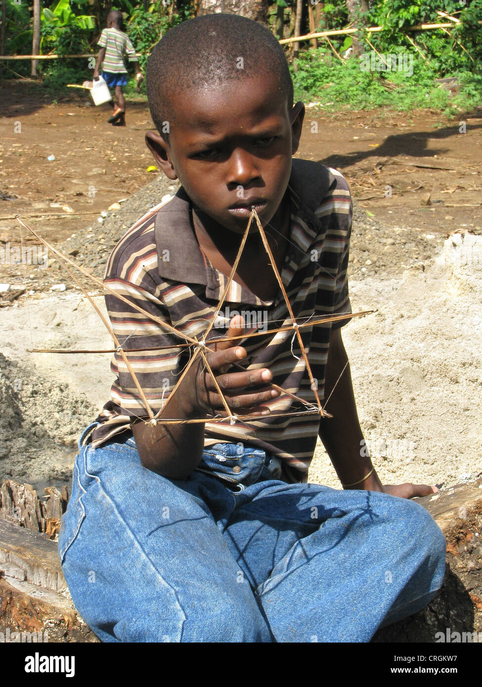 boy with self-made toy looks into camera frowningly, Haiti, Grande Anse ...