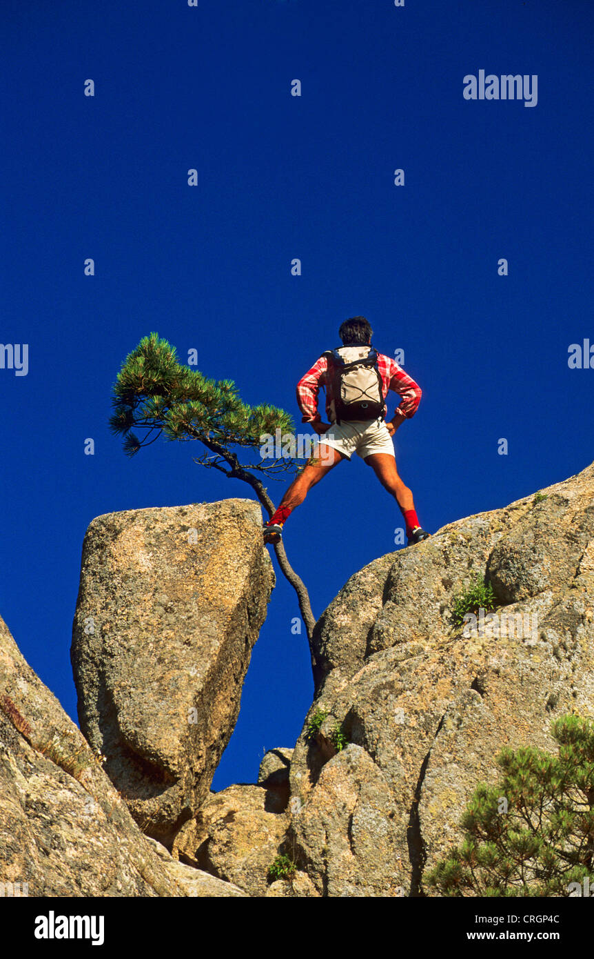 man standing with his legs apart on rock formation of Bavella mountains ...