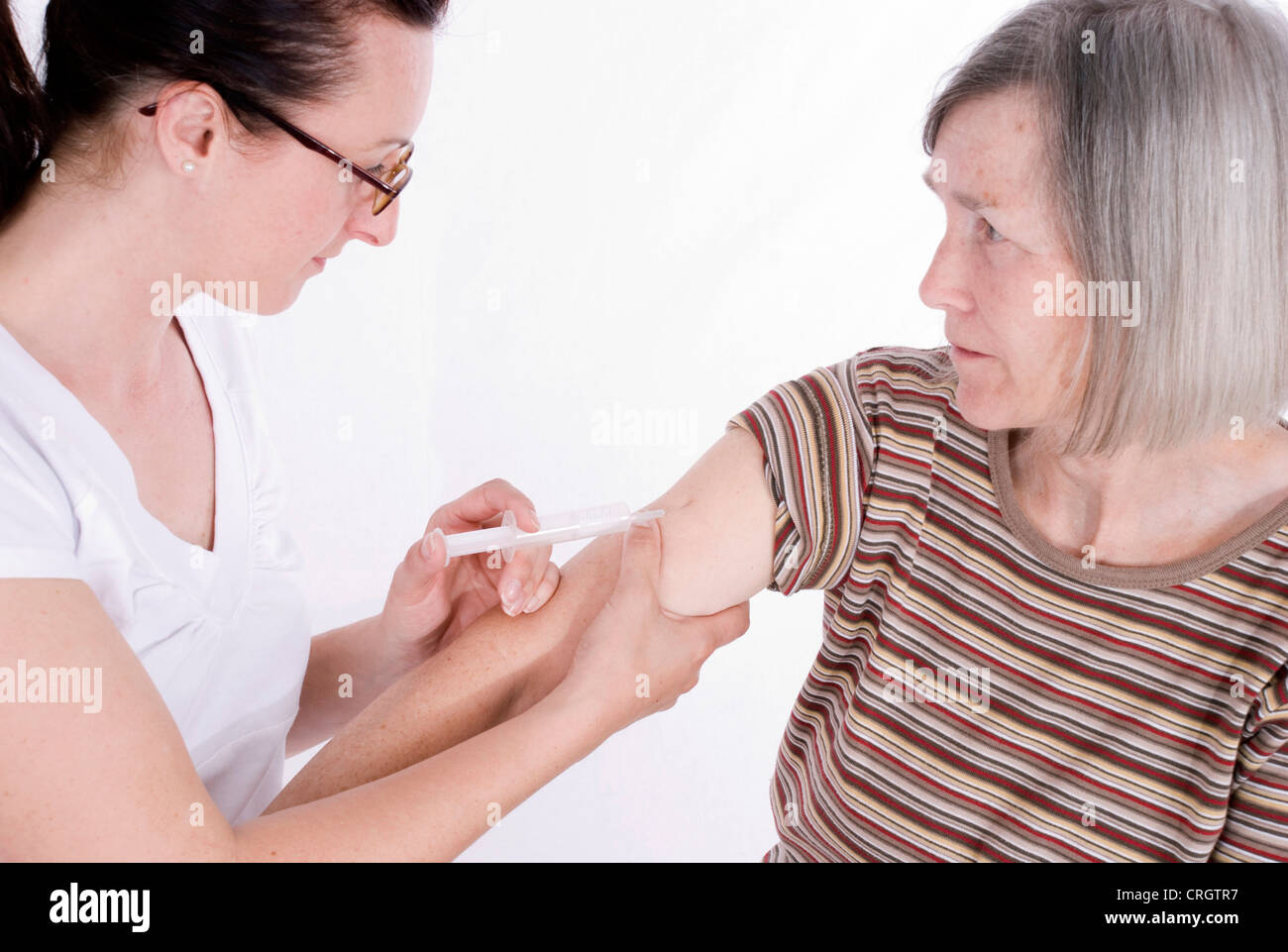 doctor giving an injection in the arm of an elder woman Stock Photo - Alamy