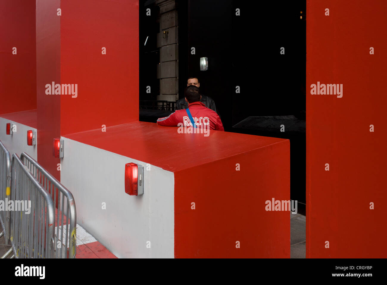 Red construction safety hoarding and young men in a central London ...