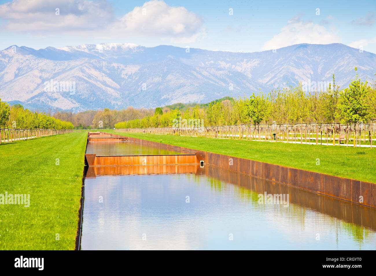 Italy - Water pool in green field with Alps mountains on background ...