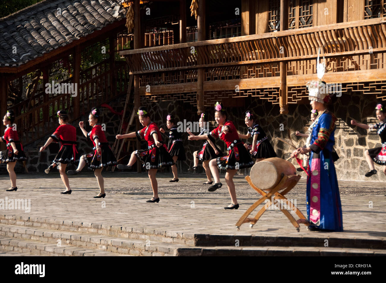 Miao dancers and a Miao girl with silver crown playing traditional drum ...