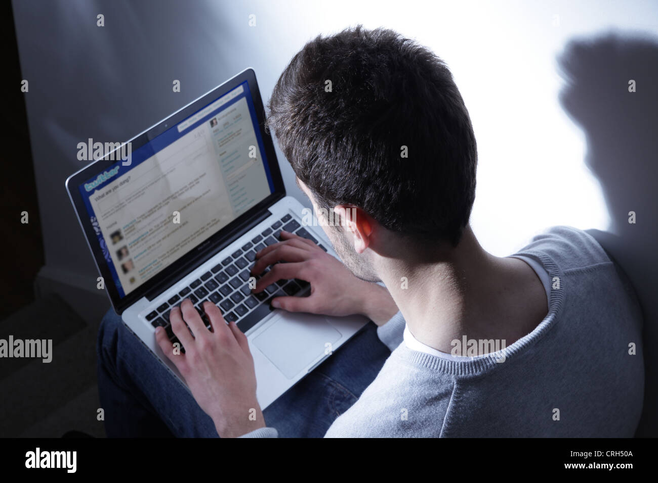 Young male sitting using a laptop looking at Twitter Stock Photo - Alamy