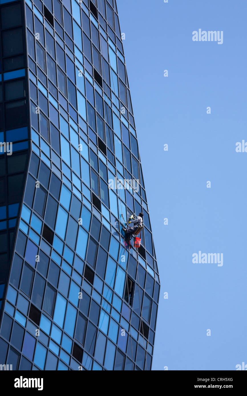 Window washer on safety cable cleaning exterior of glass skyscraper ...