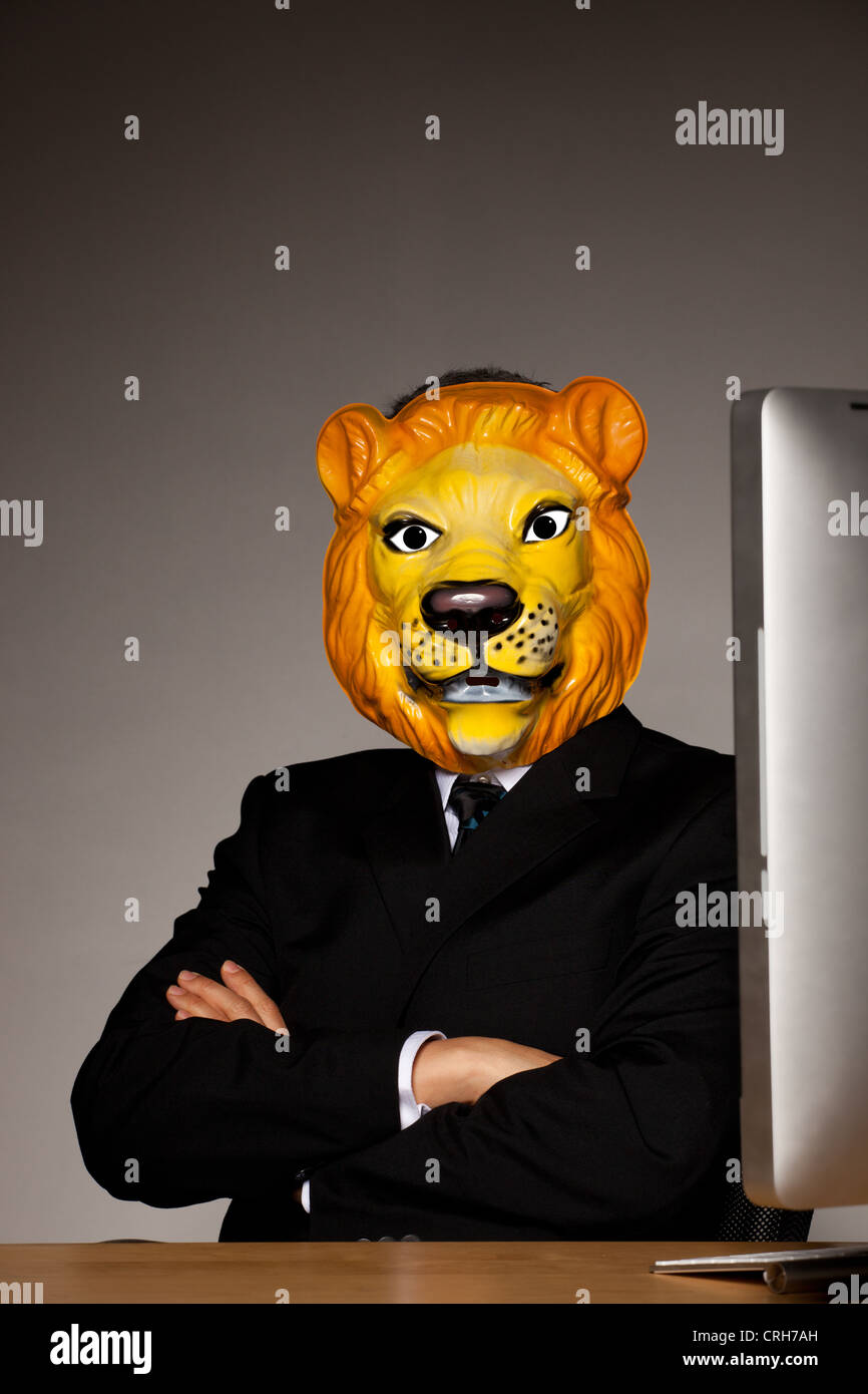 Man in business suit with lion mask sitting at work desk with computer ...