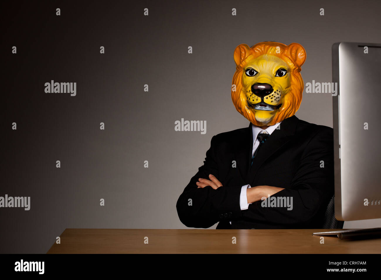Man in business suit with lion mask sitting at work desk with computer ...