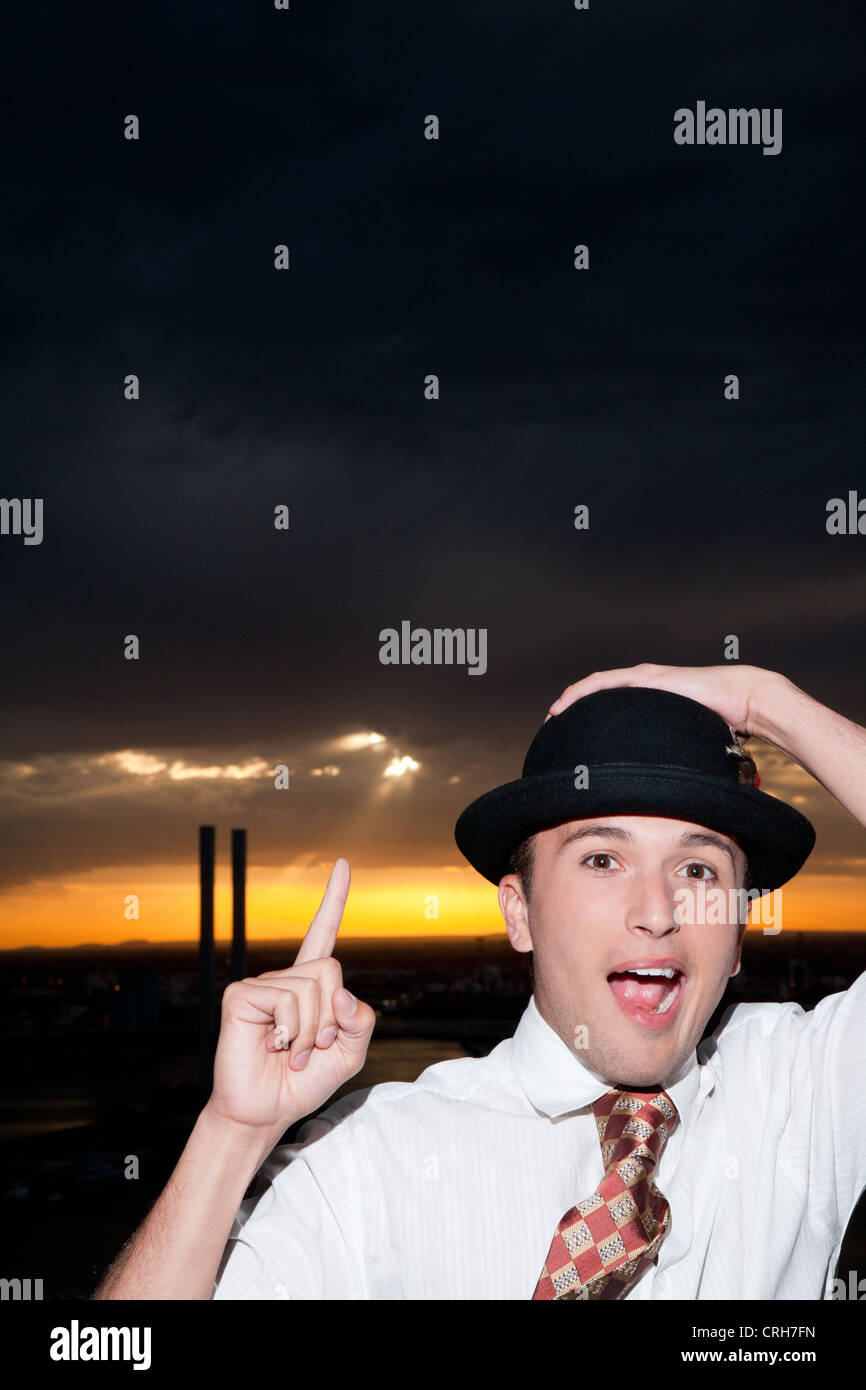 Portrait of young man wearing hat, pointing upward at dark sky Stock ...
