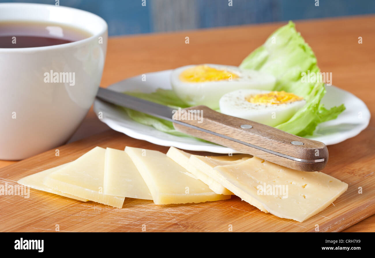 Simple breakfast background with black tea cup, cheese and boiled egg ...