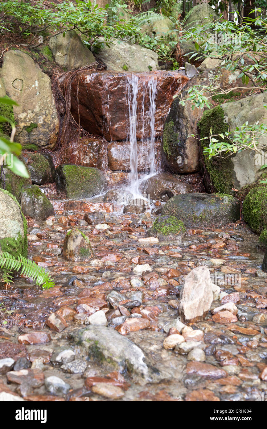 A small waterfall trickles water through the traditional Japanese ...