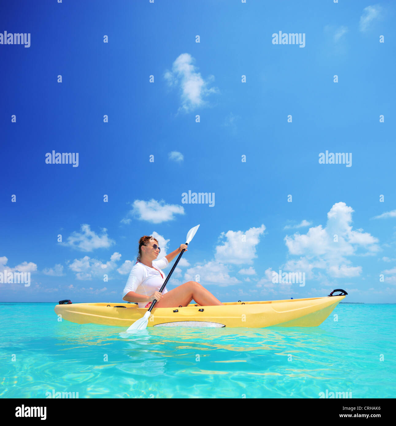 A young female in a yellow kayak kayaking near a Kuredu island ...