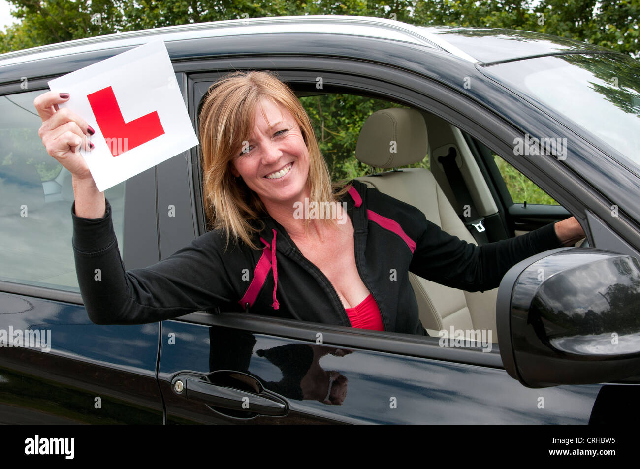 Mature female driver smiling & holding a learner driver L plate Stock ...