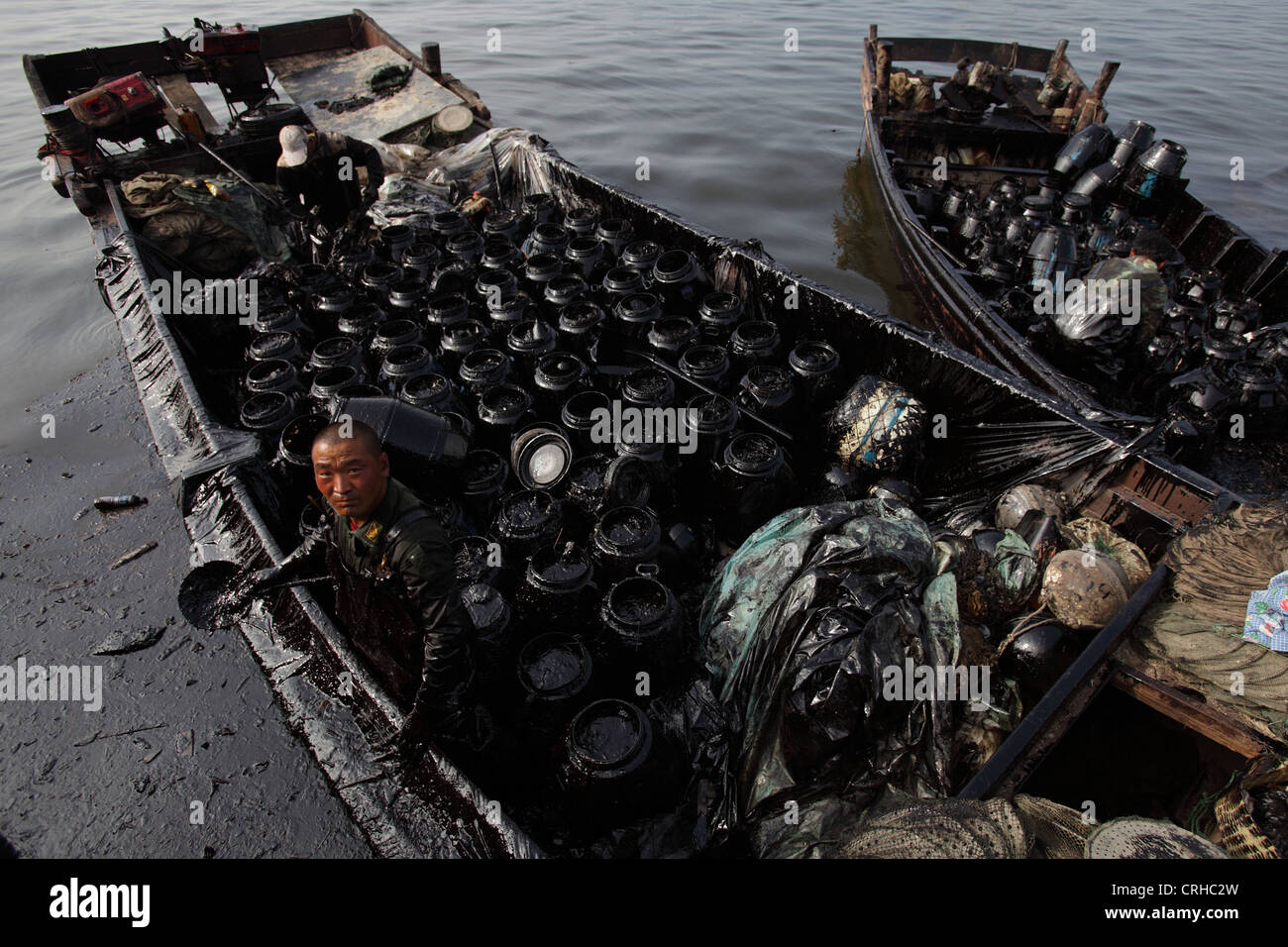 Men fill barrels with oil sludge during the oil spill disaster in ...