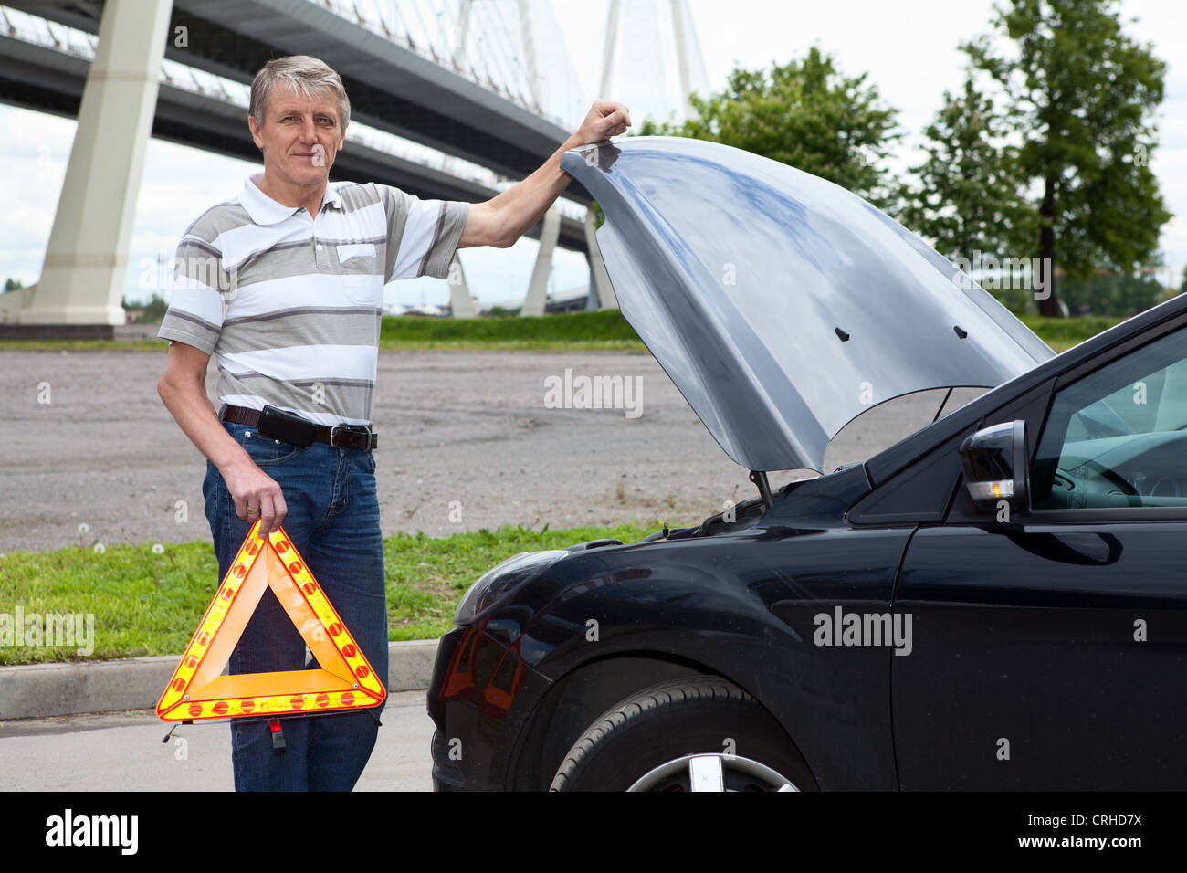 Mature man holding emergency triangle and opened car hood Stock Photo ...