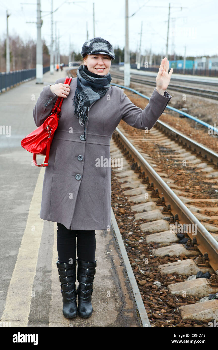 Woman in coat and cap wave goodbye standing on train station Stock ...