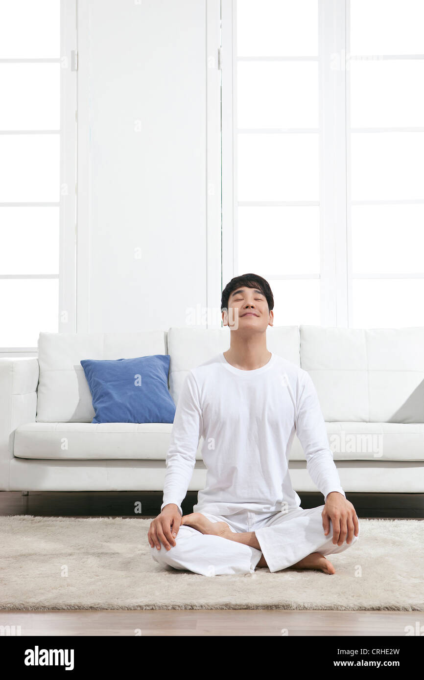 Young man sitting on carpet Stock Photo - Alamy