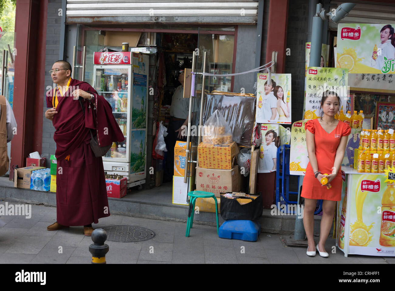Buddhist monk in robes and a girl working advertising drinks, Guozijian ...