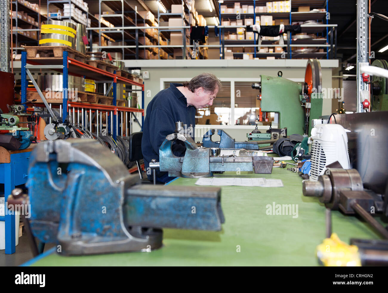 Man, sitting at a large work bench in a workshop, taking a break Stock ...