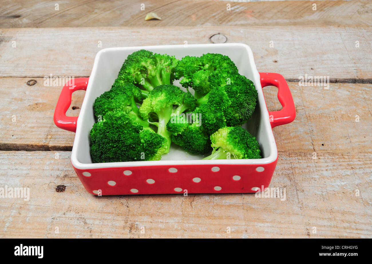 Broccoli in red porcelain tray on wooden table Stock Photo - Alamy
