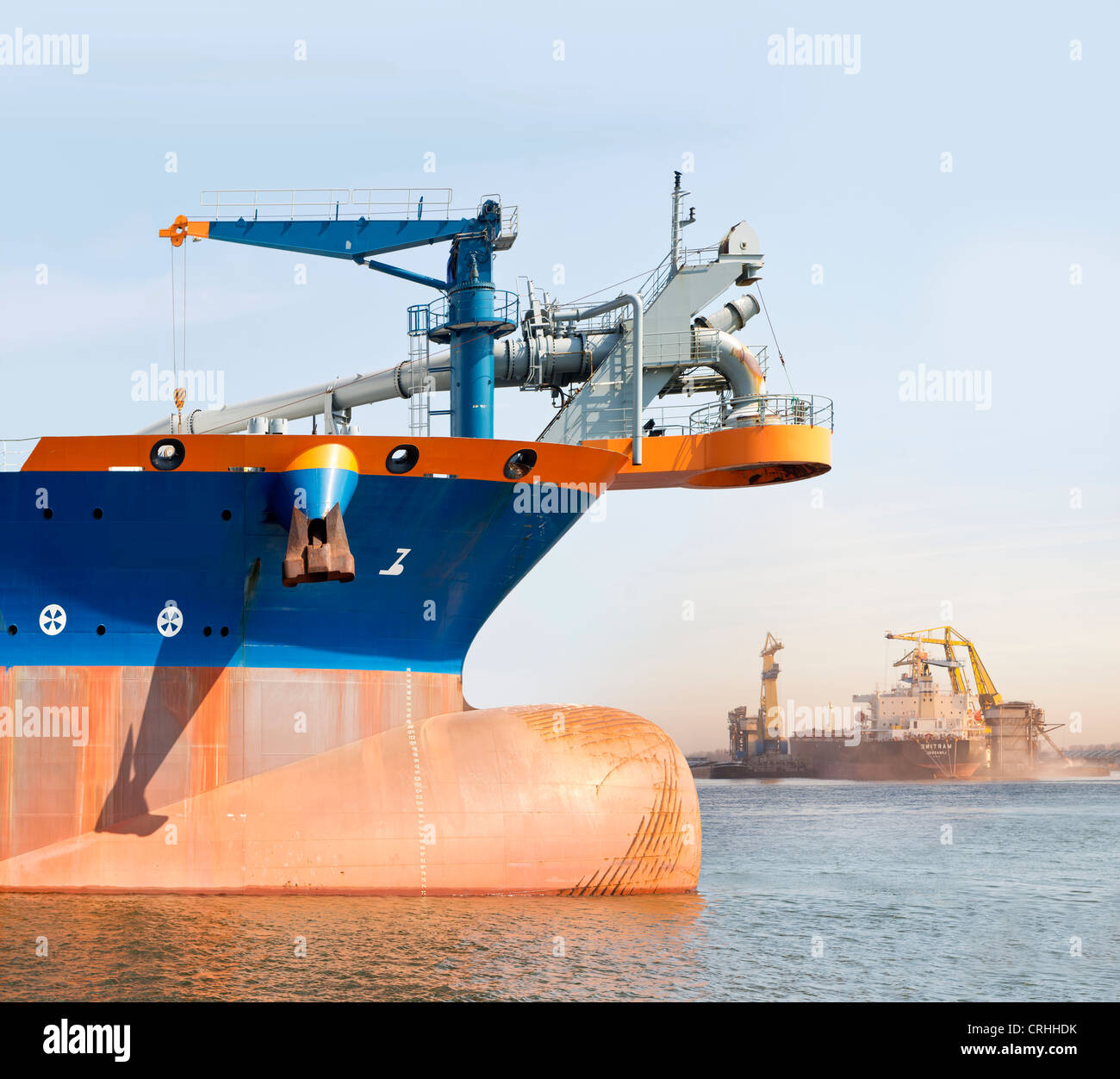 Bow of an industrial ship, with large cranes unloading raw materials ...