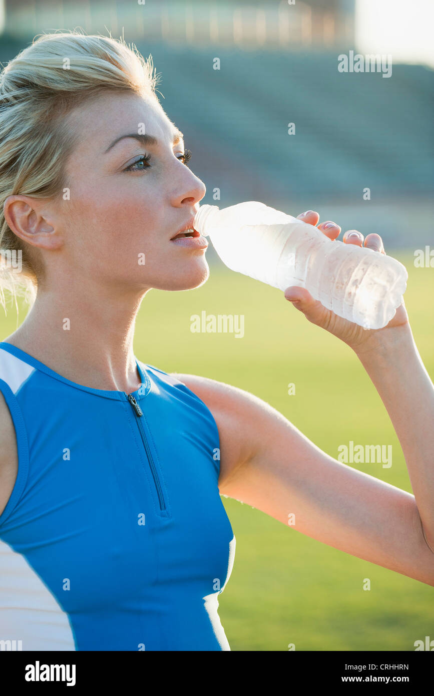 Young woman hydrating, taking break from exercising Stock Photo - Alamy