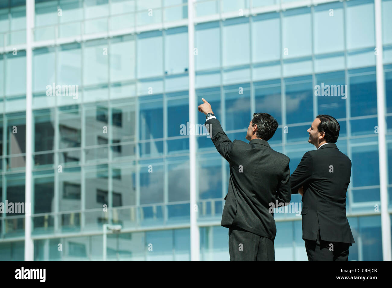 Two business executives standing back to back with his arms crossed ...