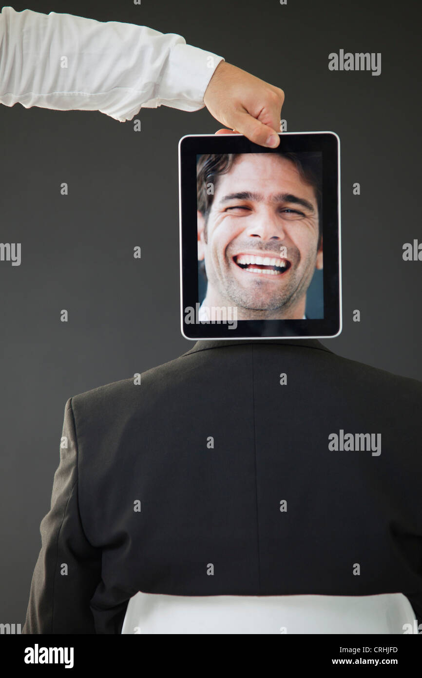 Man concealed behind digital tablet displaying image of laughing man ...