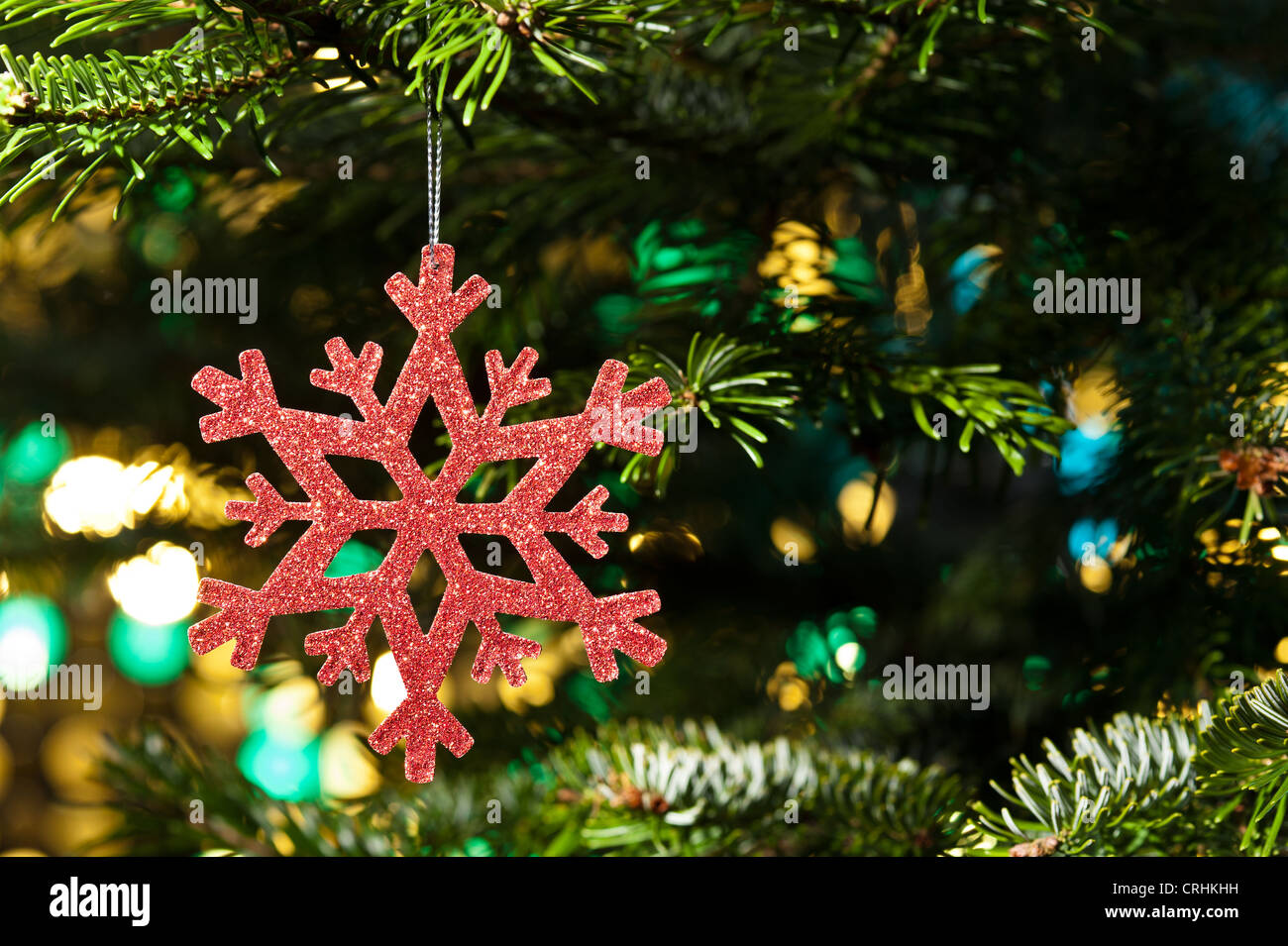 Red artificial snow flake in a christmas tree infront of a glitter ...