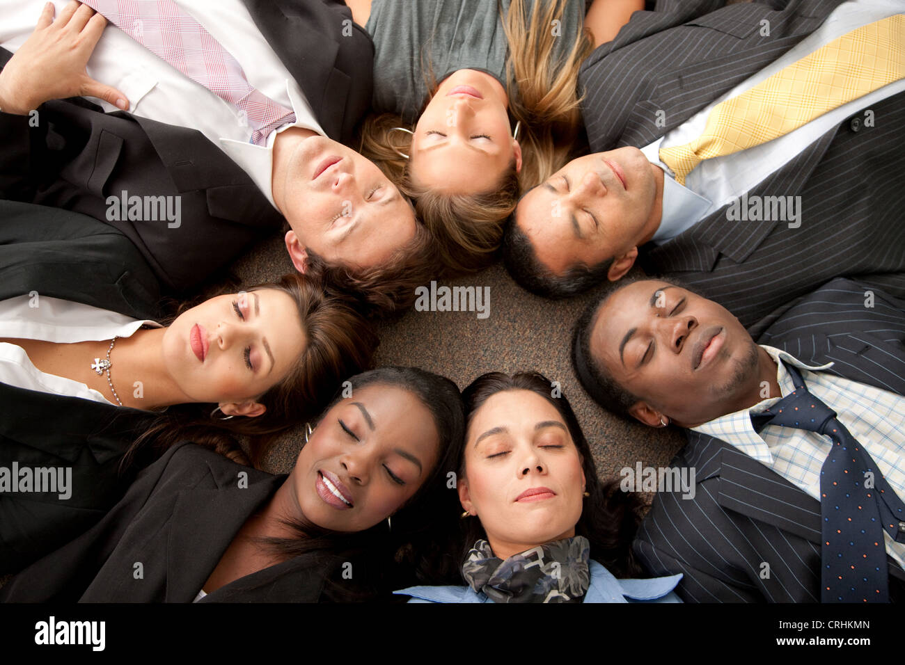 business group with heads together on the floor and their eyes closed ...