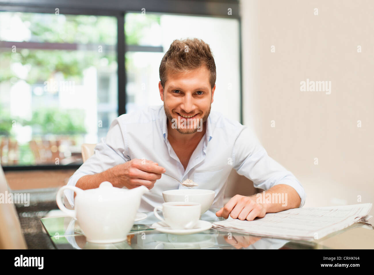 Smiling man eating breakfast at table Stock Photo - Alamy
