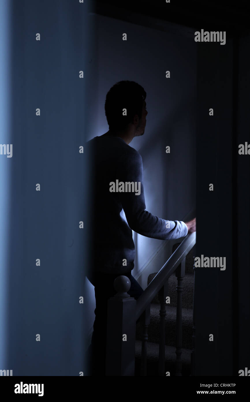 Young man walking upstairs late at night Stock Photo - Alamy