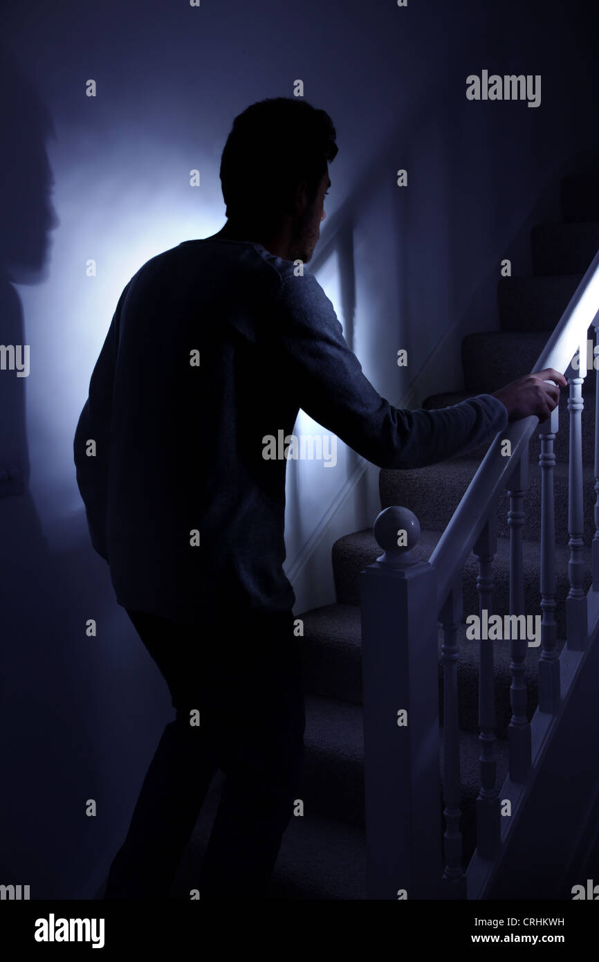 Young man walking upstairs late at night Stock Photo - Alamy