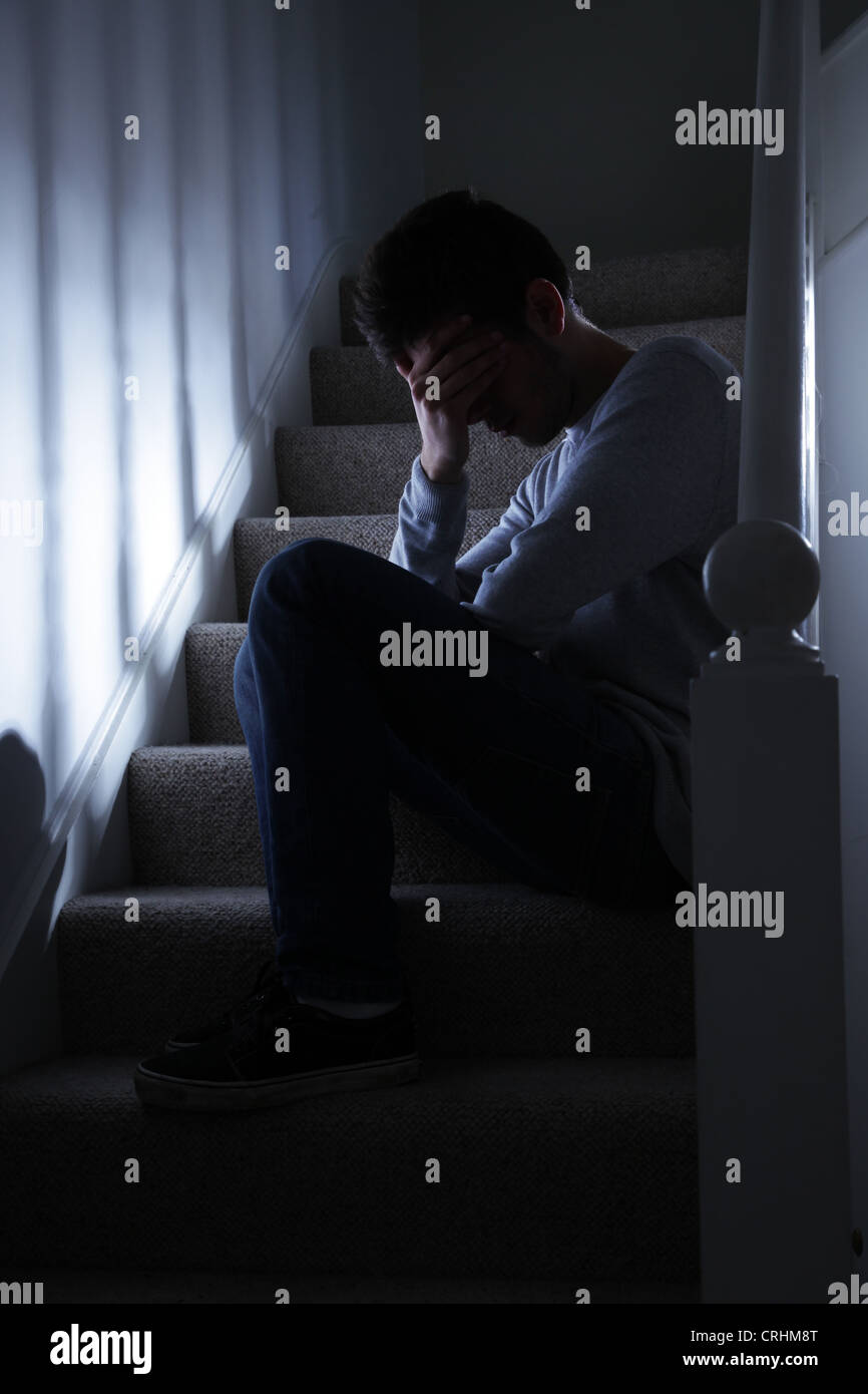 Young man sitting on the stairs, his hand covering his face Stock Photo ...