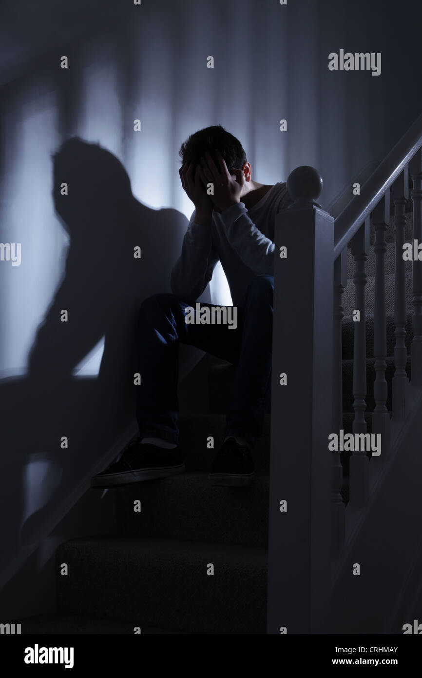 Young man sitting on the stairs, his hand covering his face Stock Photo ...