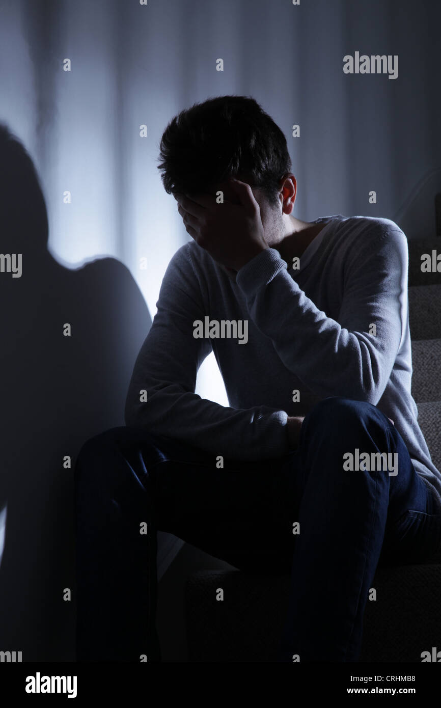 Young man sitting on the stairs, his hand covering his face Stock Photo ...