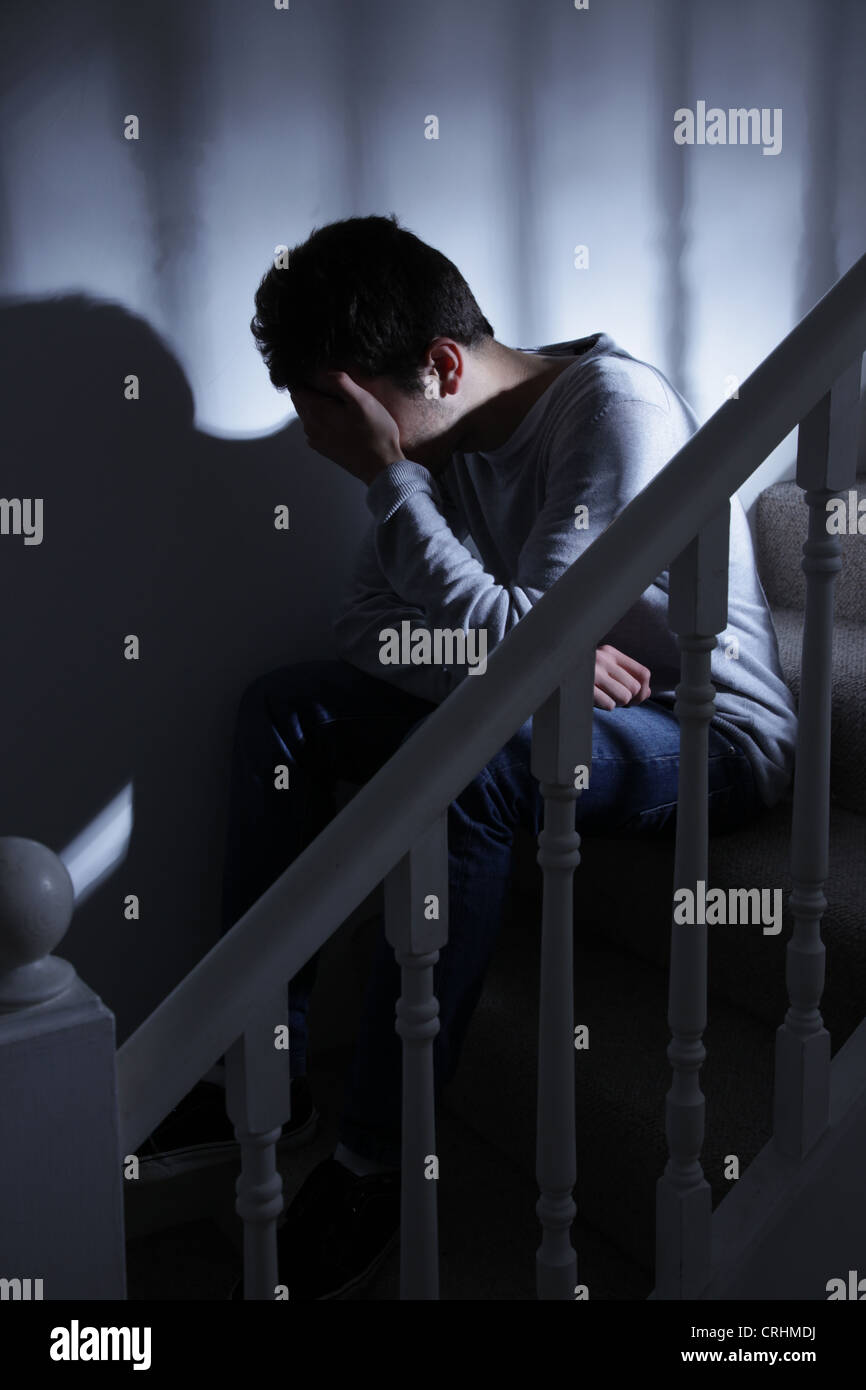 Young man sitting on the stairs, his hand covering his face Stock Photo ...