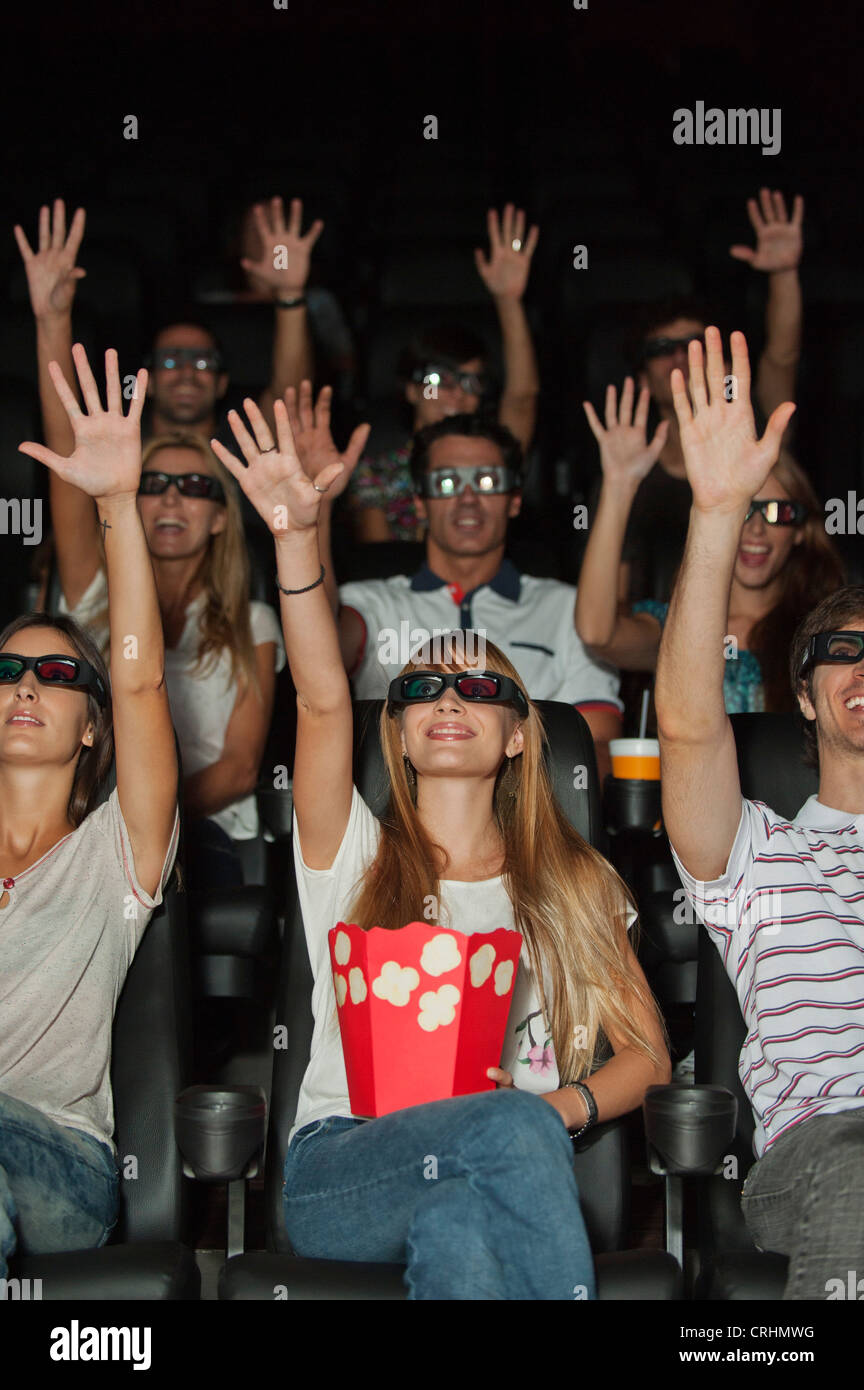 Audience wearing 3-D glasses in movie theater, arms reaching up Stock ...